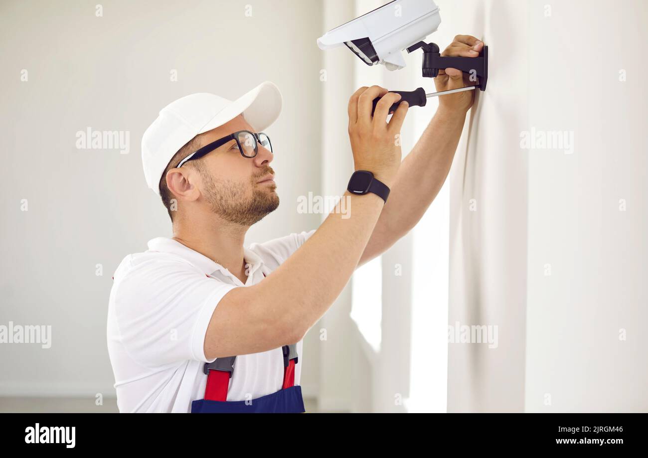 Worker installing a surveillance CCTV camera on the wall inside the ...
