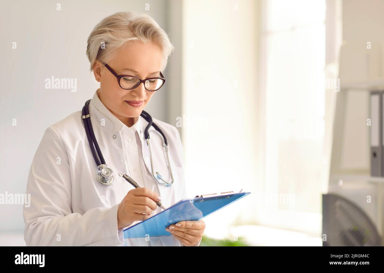 Female doctor holding a clipboard and taking notes in medical forms and ...