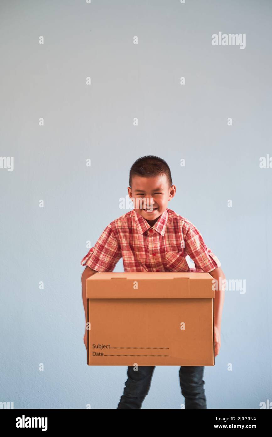 A vertical closeup of boy carrying a heavy cardboard box or packaging ...