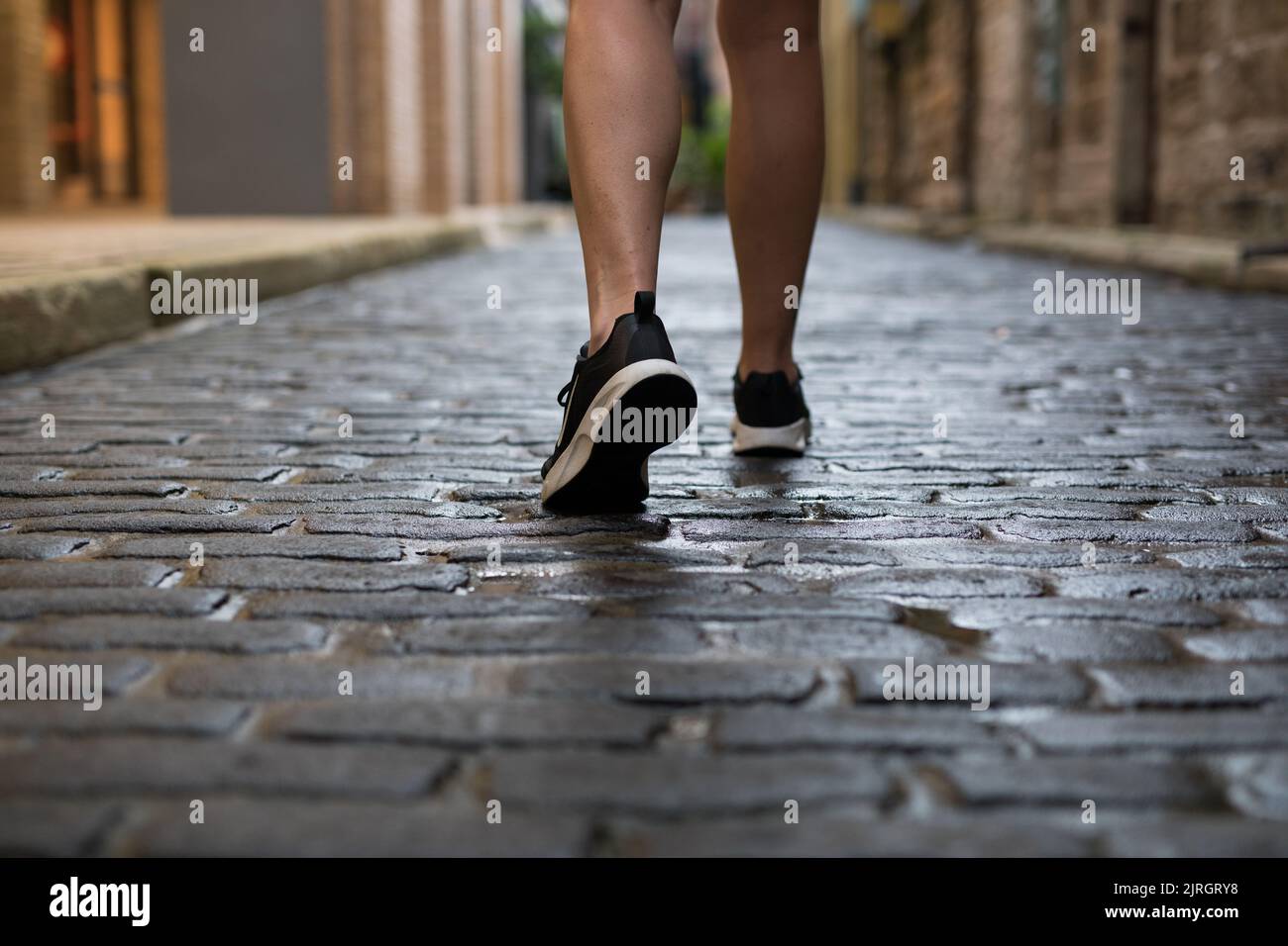 A closeup of woman's legs walking on wet cobblestones Stock Photo - Alamy