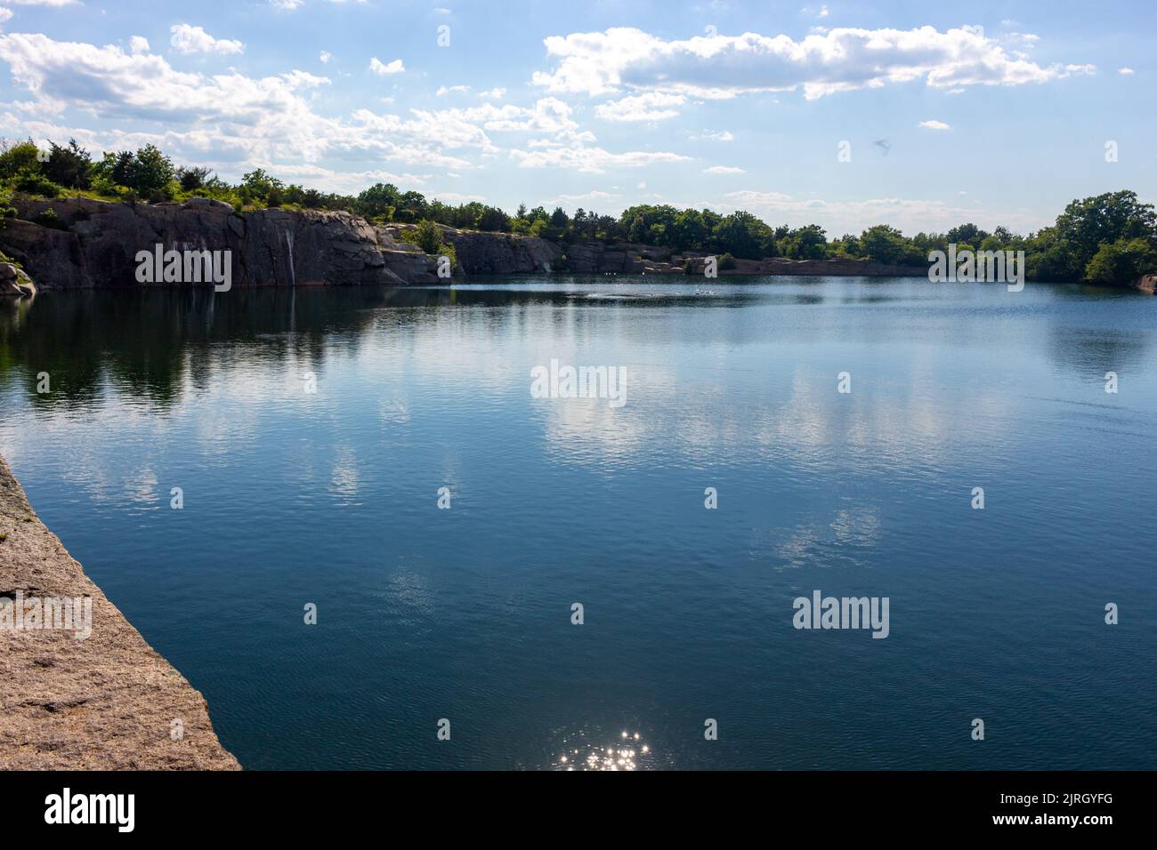 Beautiful view of lake surrounded by dense trees and old granite quarry ...