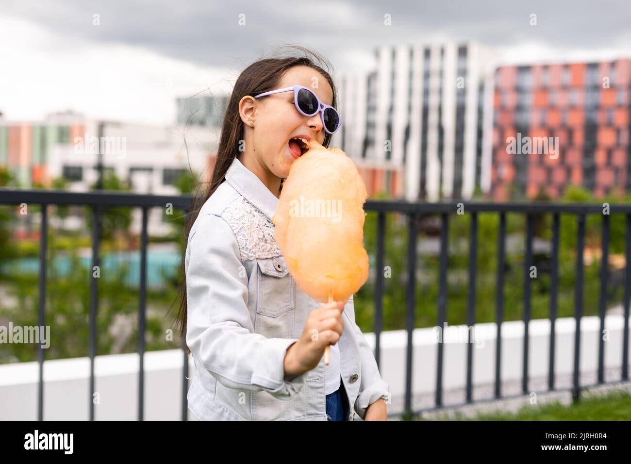 Adorable and pretty little girl eating sweet cotton candy. Happy child ...