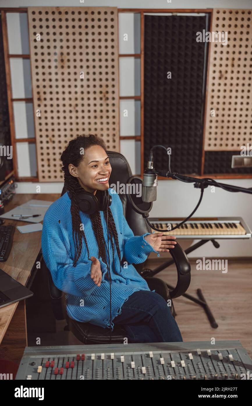 Charming African woman radio presenter talks into microphone while ...