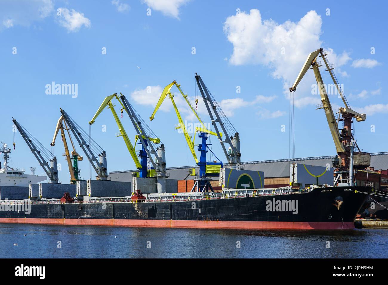 Bulk carrier with open storage tanks in port bulk terminal, port cranes ...