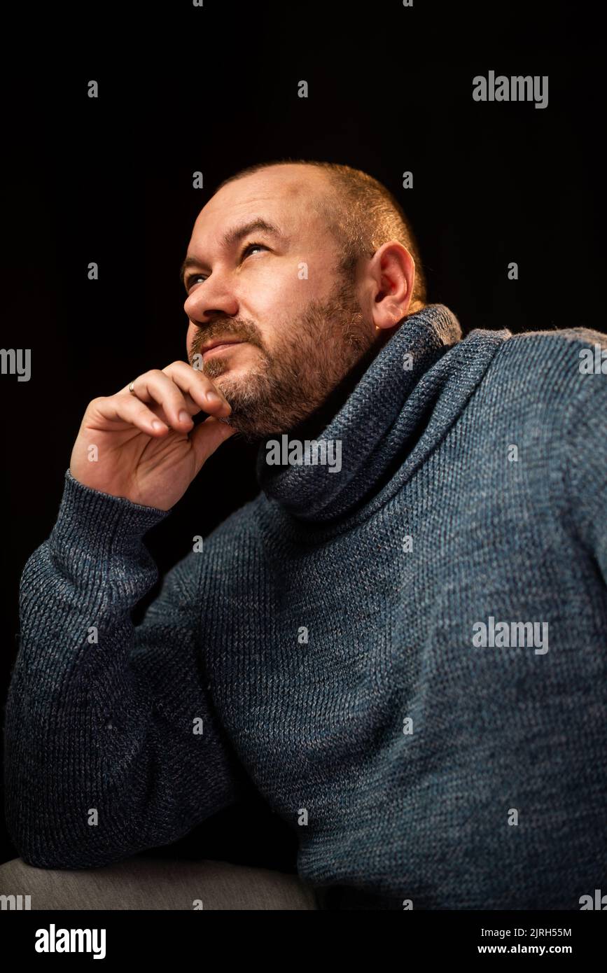 A middle-aged man in a sweater looks up. Unshaven man of normal ...