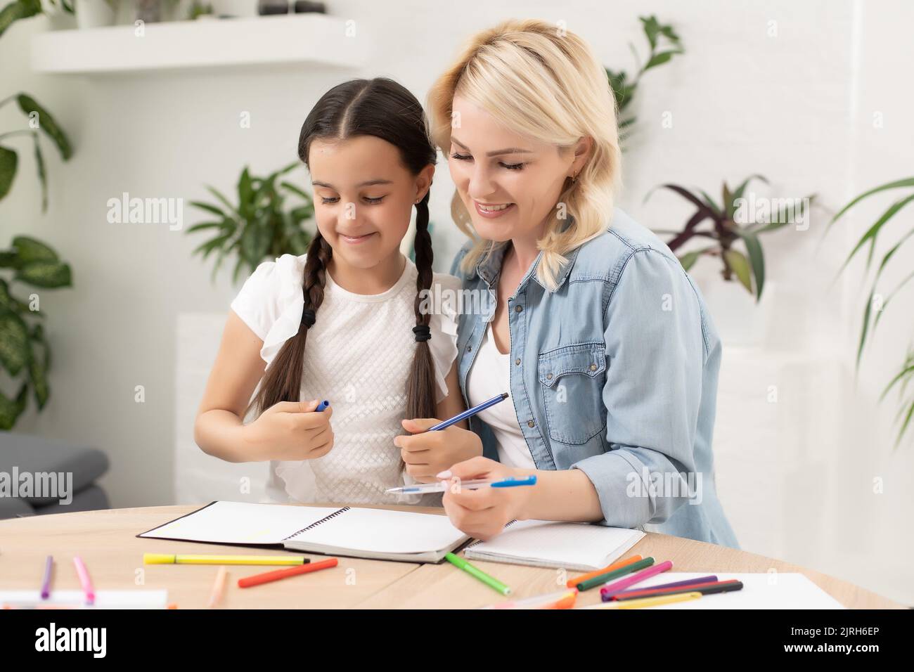 Little girl educating at home with her mother symbols drawn over her ...