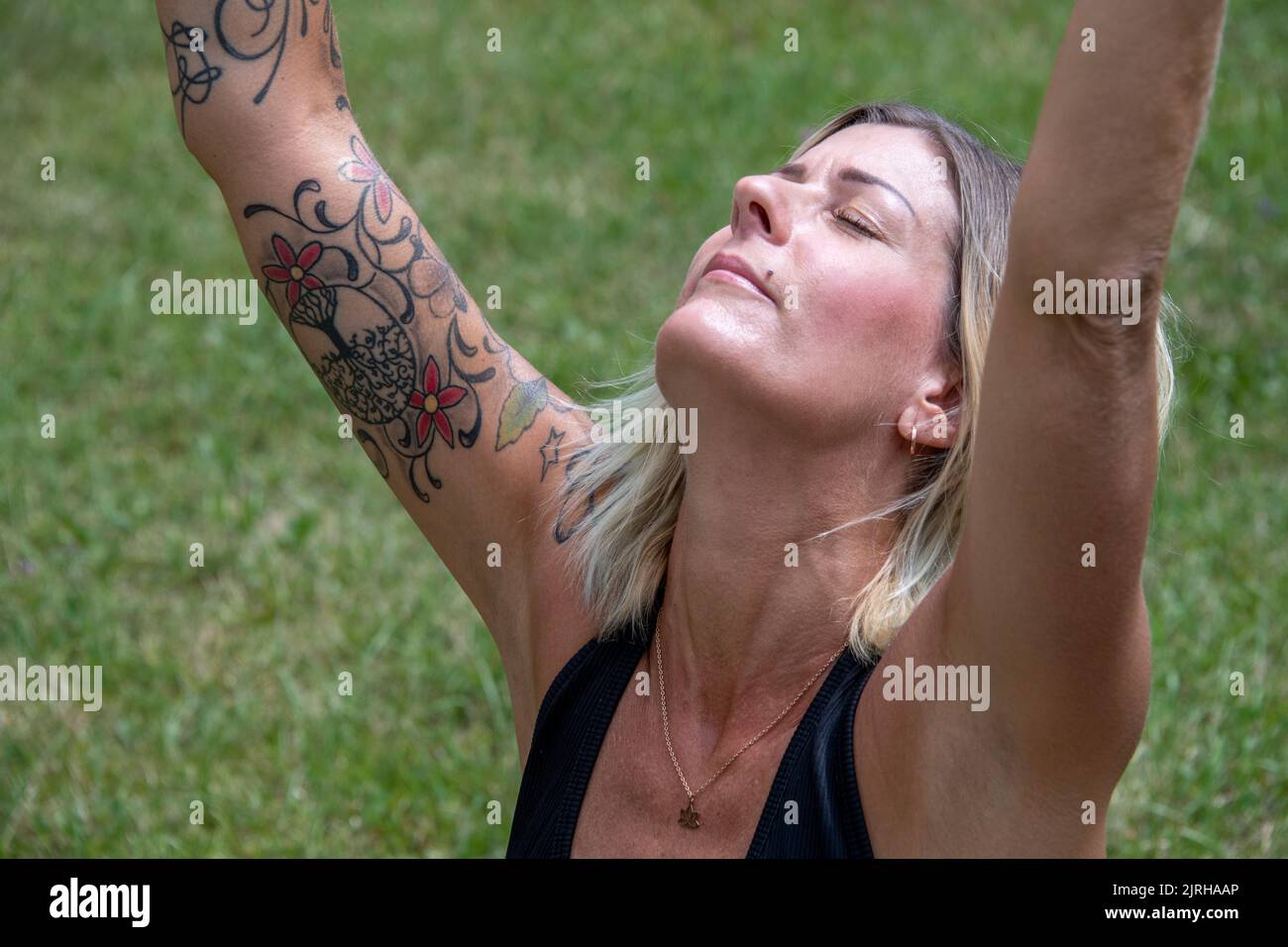 Young european lady with outstretched arms, wearing tattoos and ...