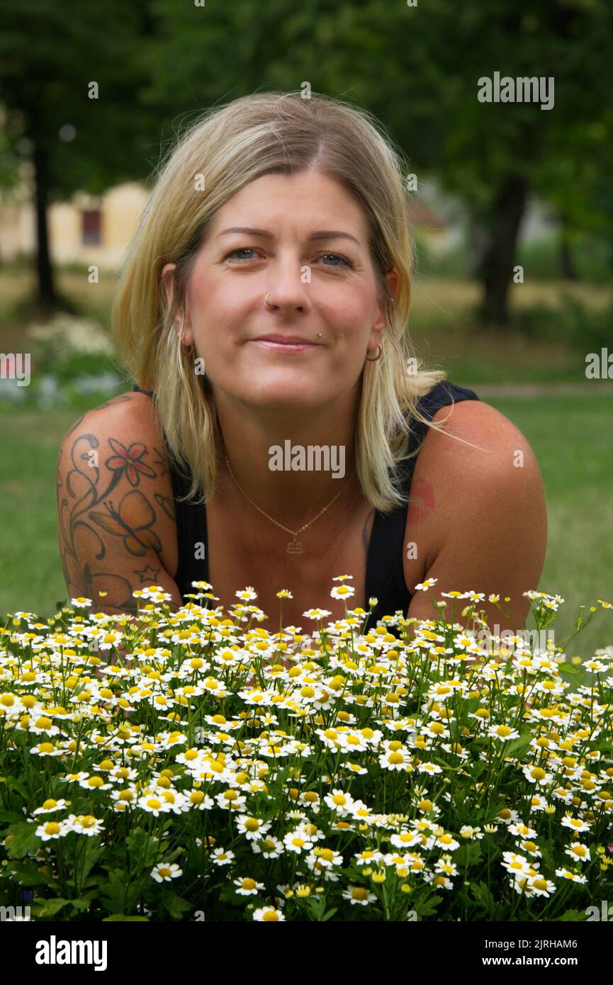 Portrait of a blond woman behind beautiful daisy flowers in yellow and ...