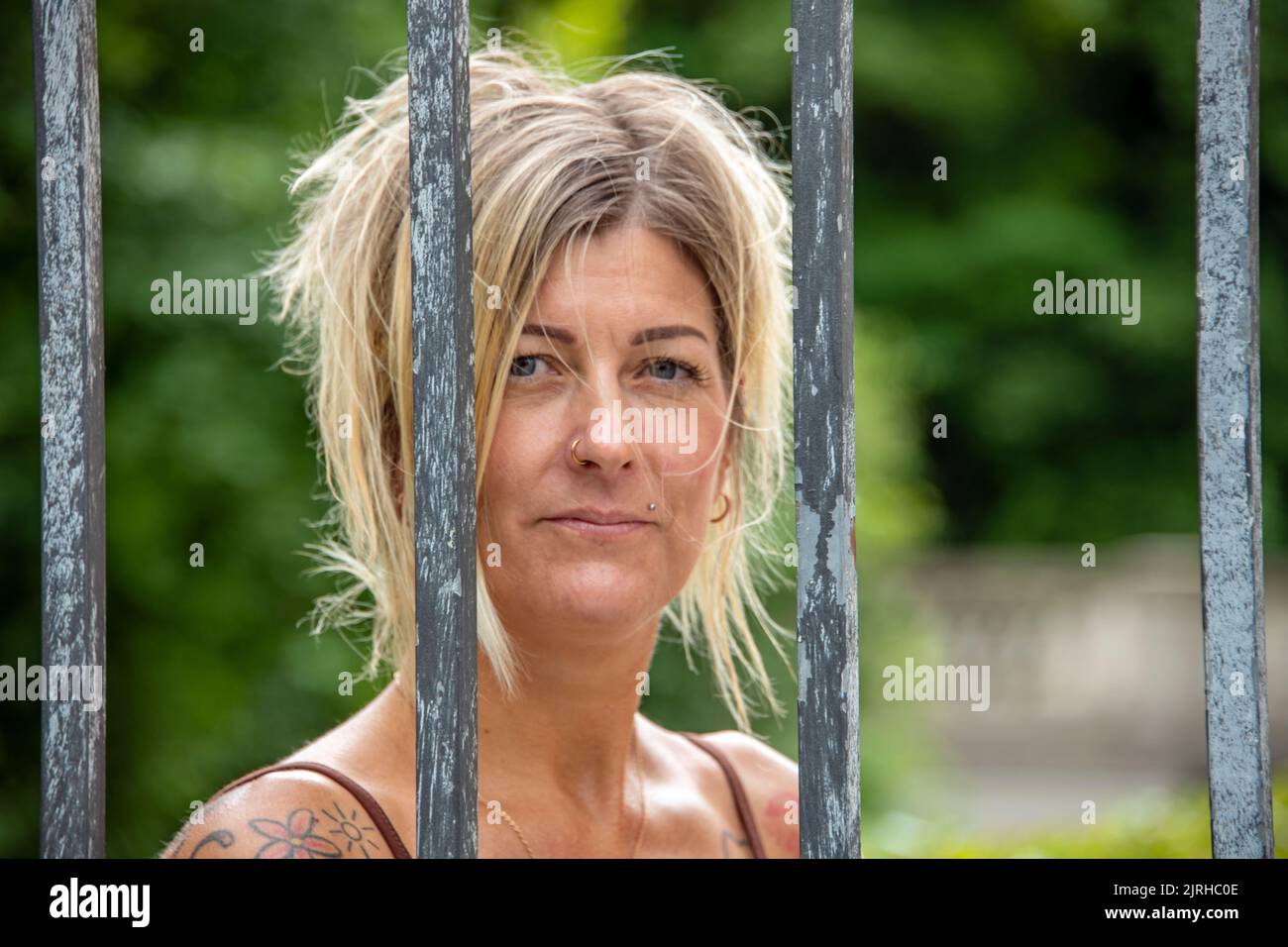 Head shot of a blond european woman with face expression behind bars ...