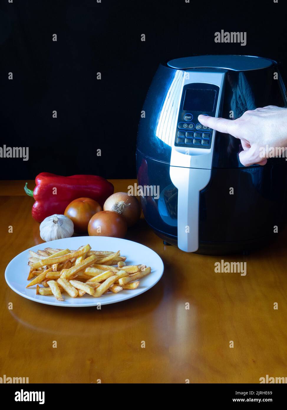 A woman's hand programming an air fryer with french fries and ...