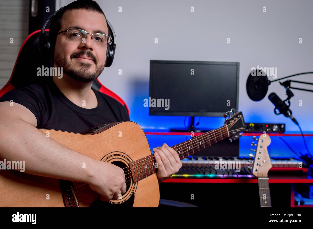 portrait happy latin young man sitting in his music studio with his ...