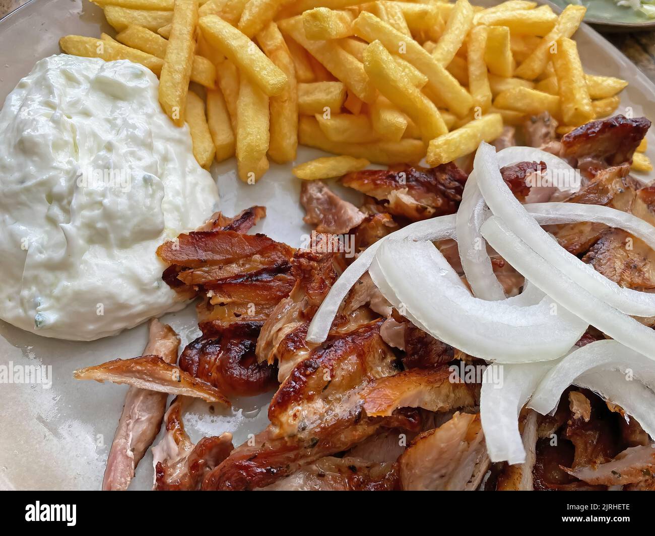 Closeup of isolated ready to eat greek pork gyros plate with onions ...