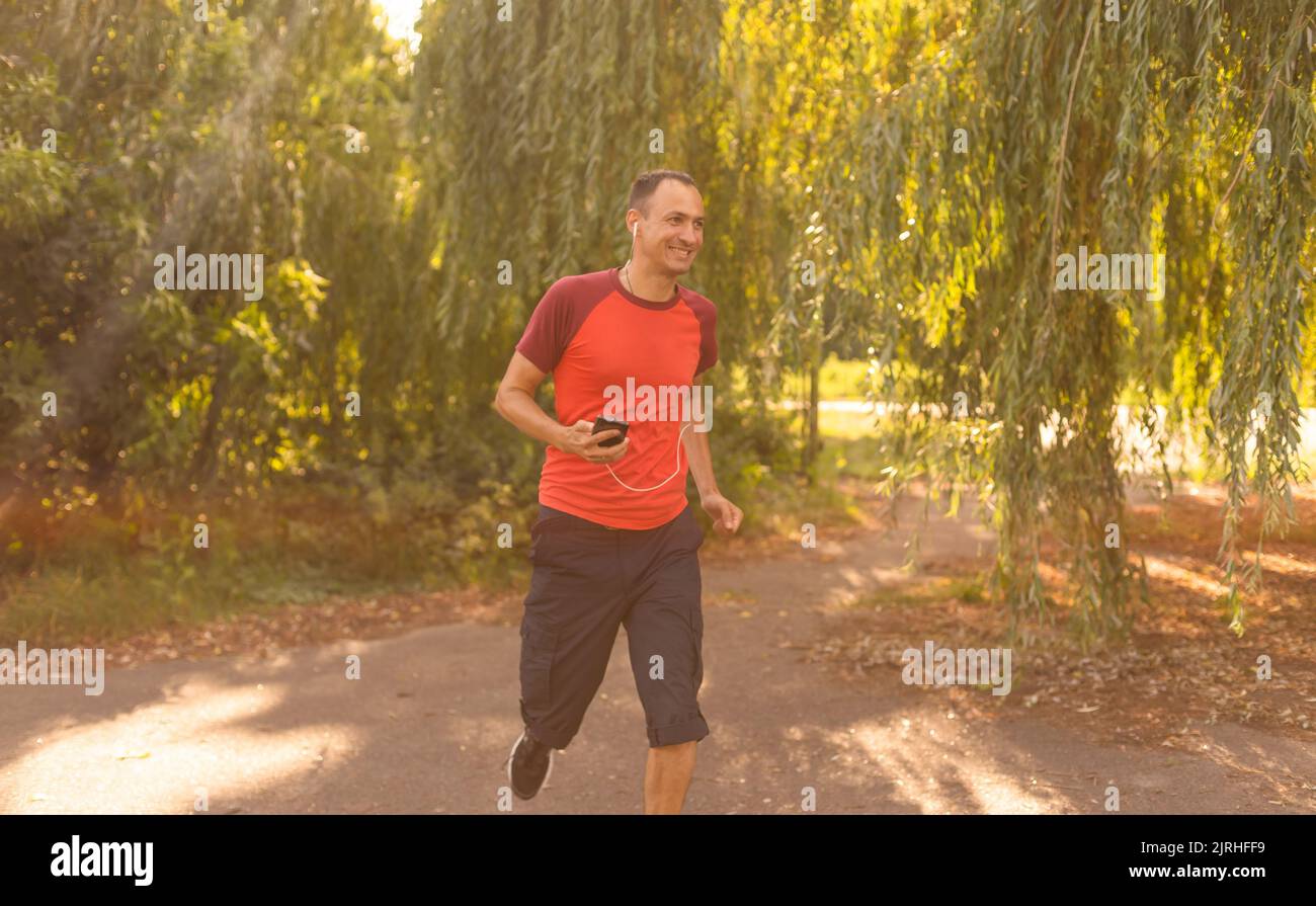 Portrait of a man running in a park. Close up of a smiling man running ...