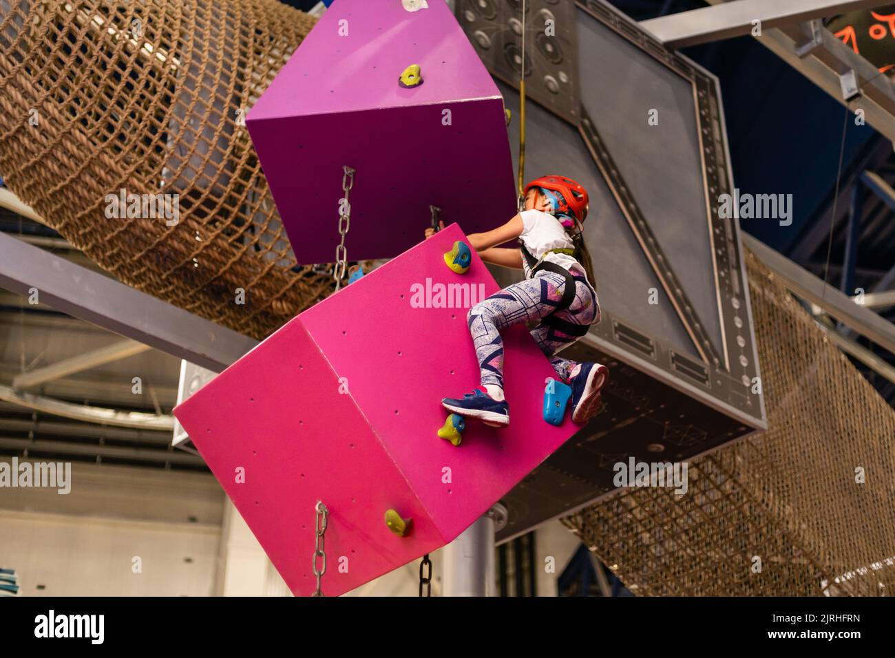 Little girl ascending in rock climbing gym Stock Photo - Alamy