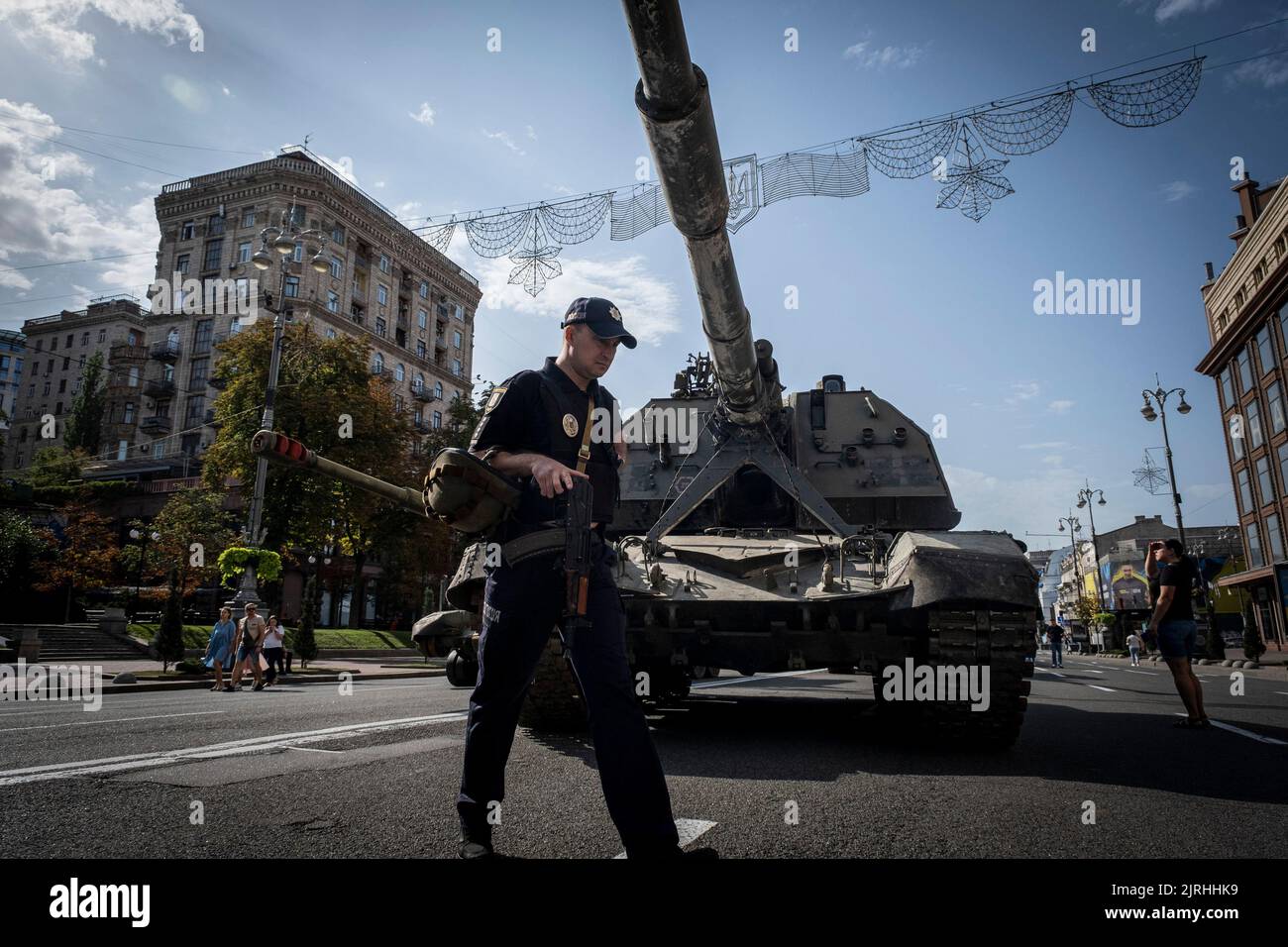 A Ukrainian policeman with a rifle walks past a destroyed Russian ...