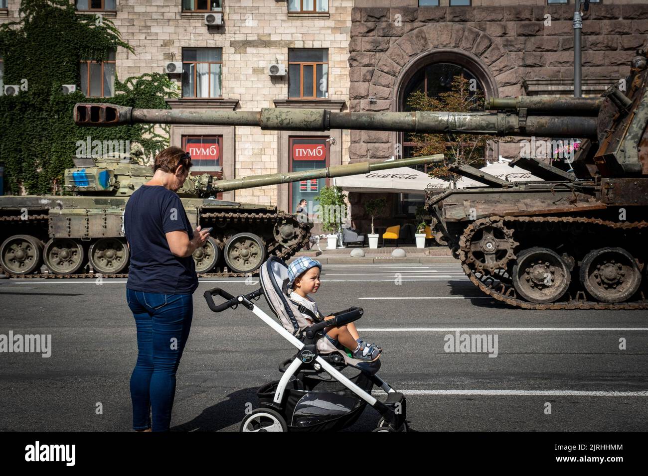A mother with her baby seen on the streets taking photos of destroyed ...