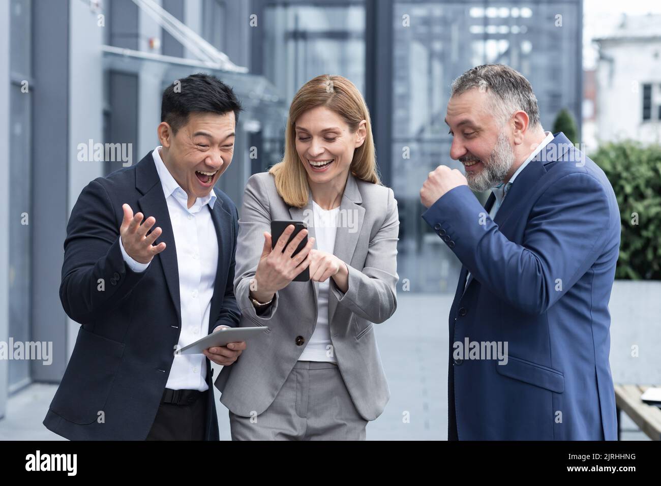Three colleagues employees watch funny videos or look at photos ...