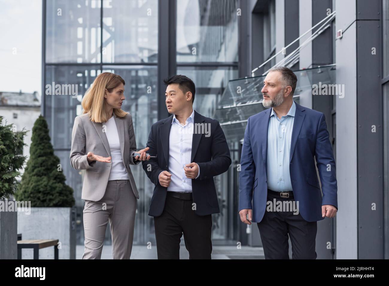 Three diverse business people walking and talking focused and ...