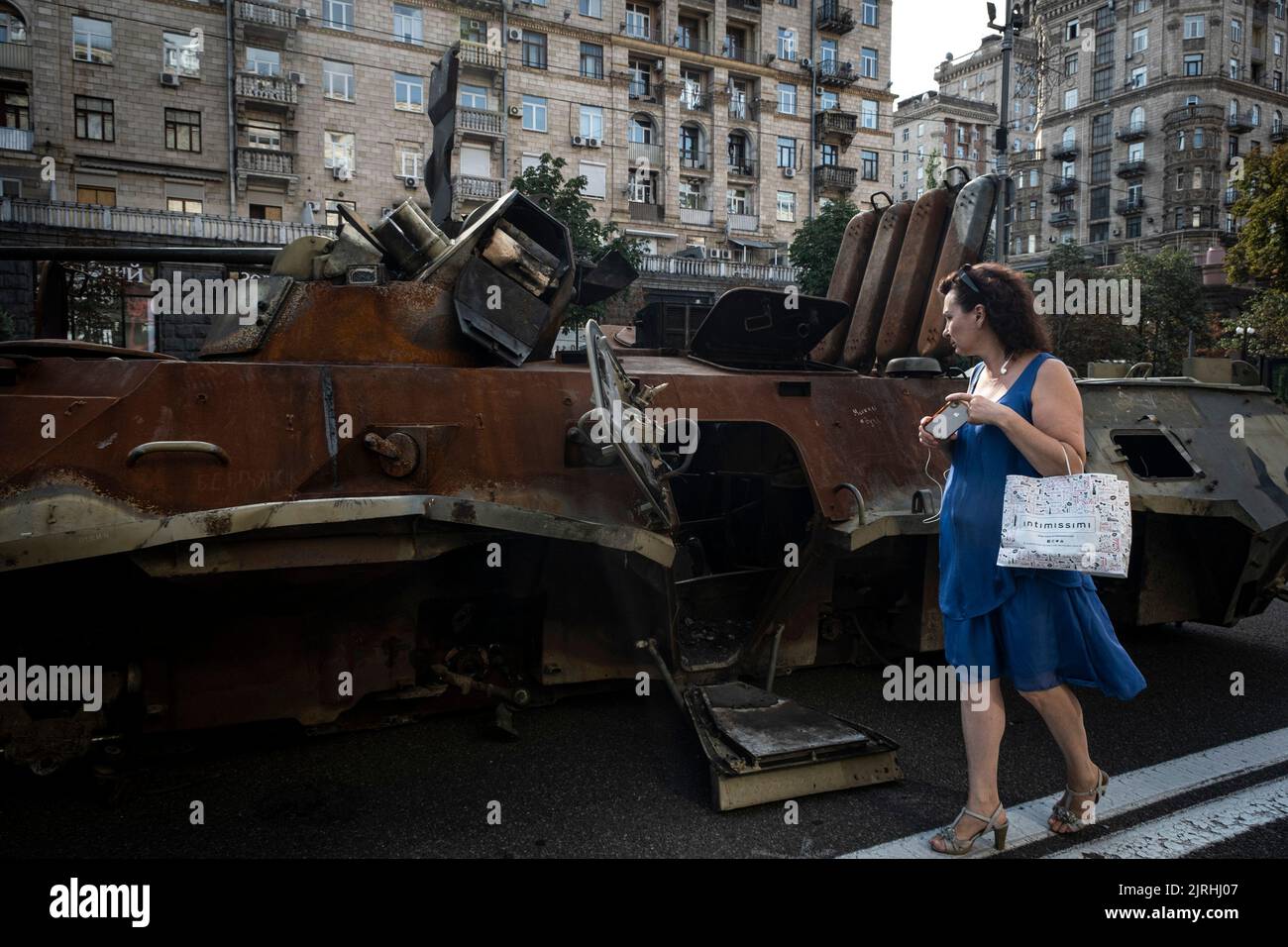 A woman looks at a destroyed Russian armored personnel carrier (APC) in ...