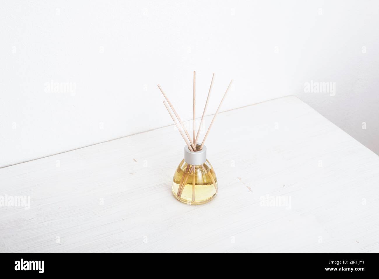 Aromatic incense, oil diffuser with reed sticks on white table ...