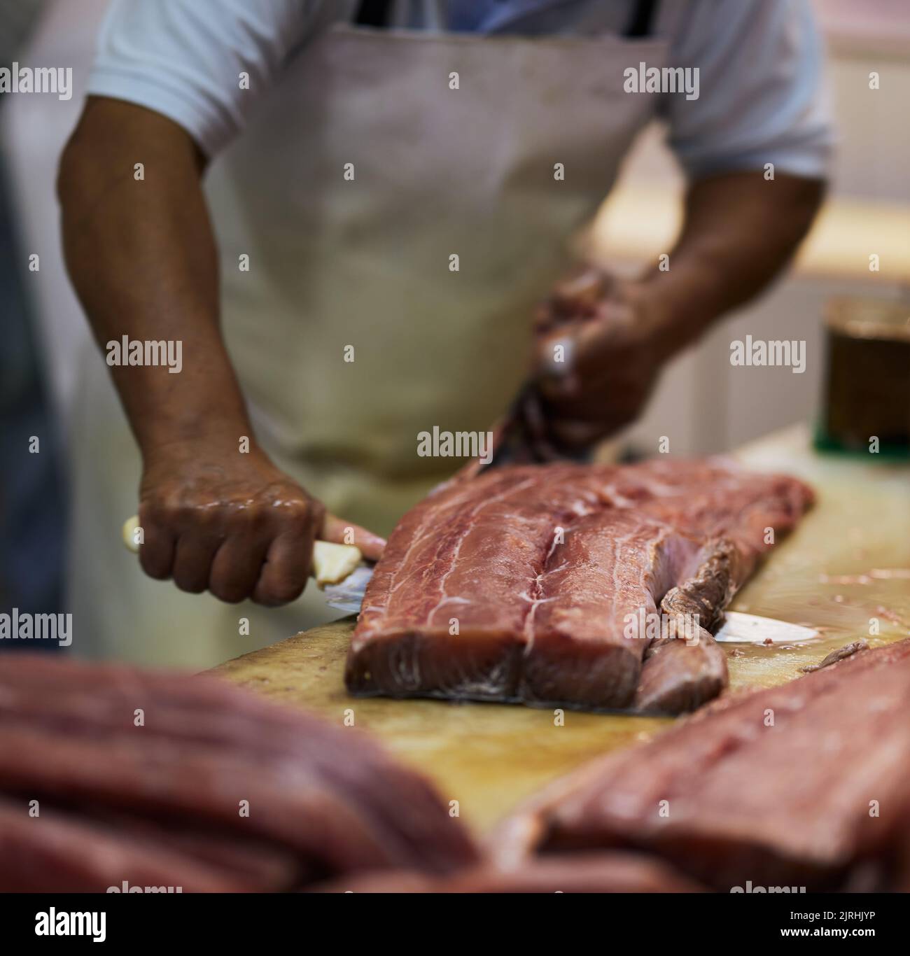 A butcher cutting a big piece of meat in a store Stock Photo - Alamy