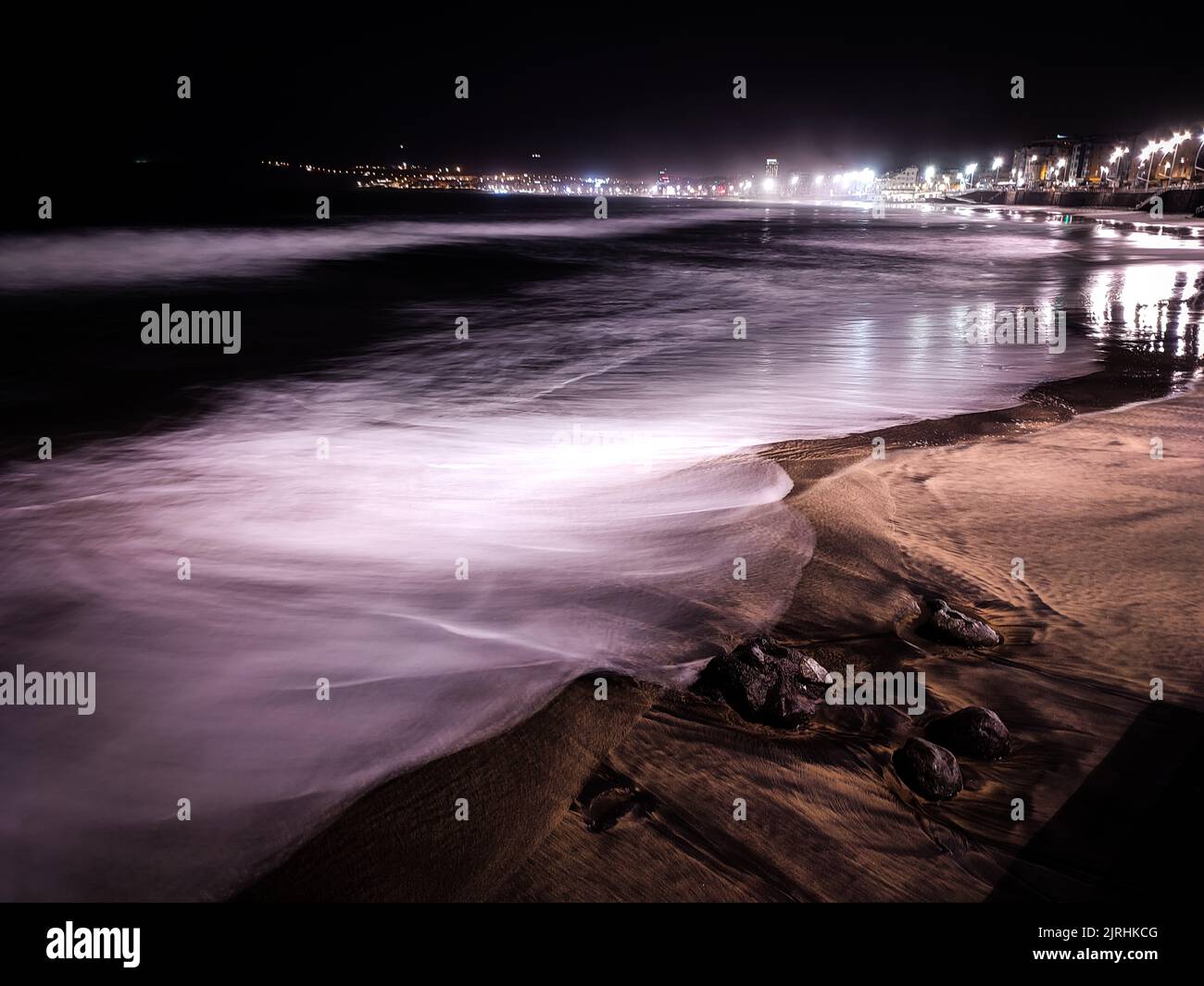 A scenic view of a beach and coastline buildings with illuminated ...