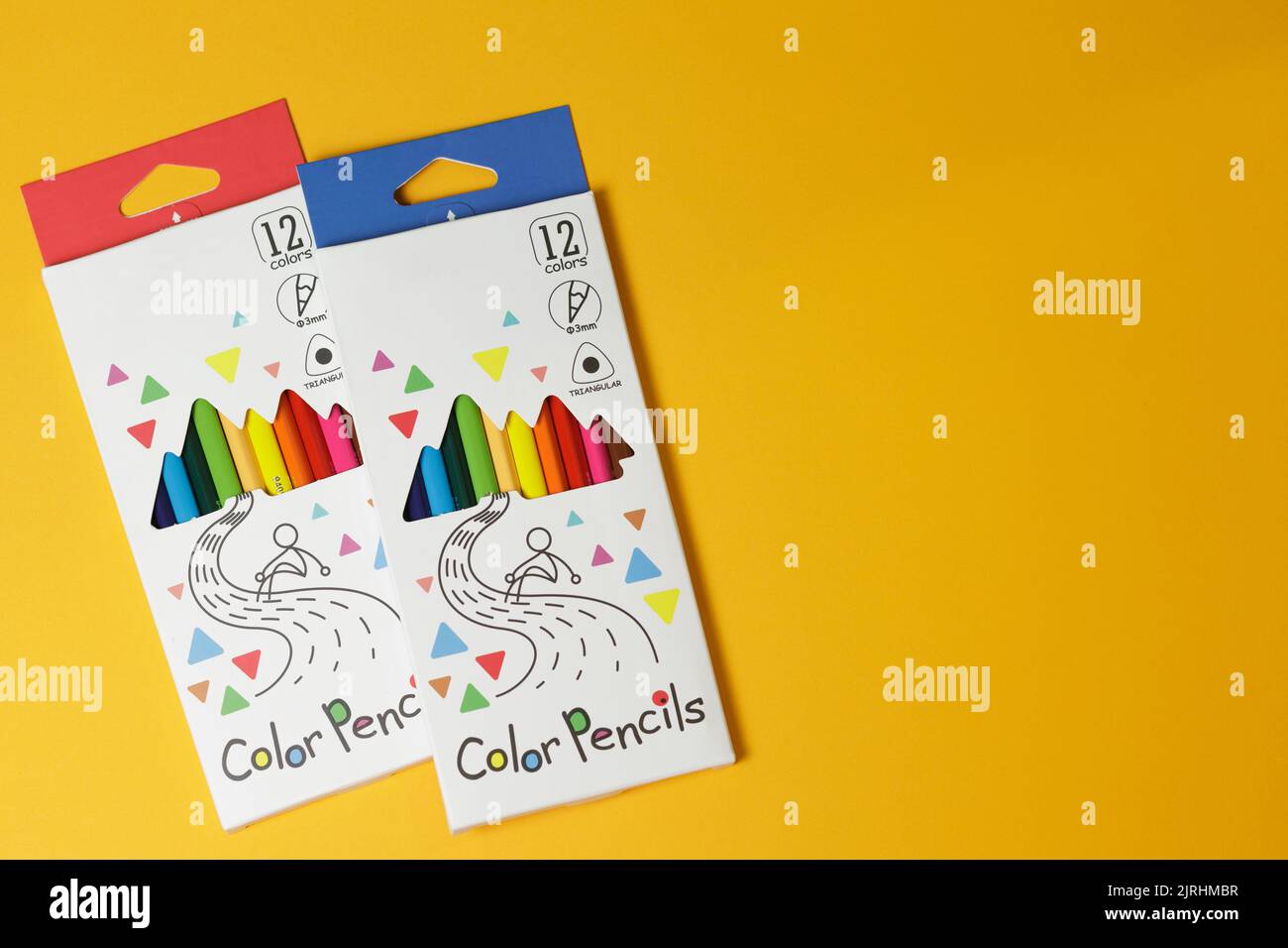 Two boxes of twelve colored pencils on a yellow background with copy ...