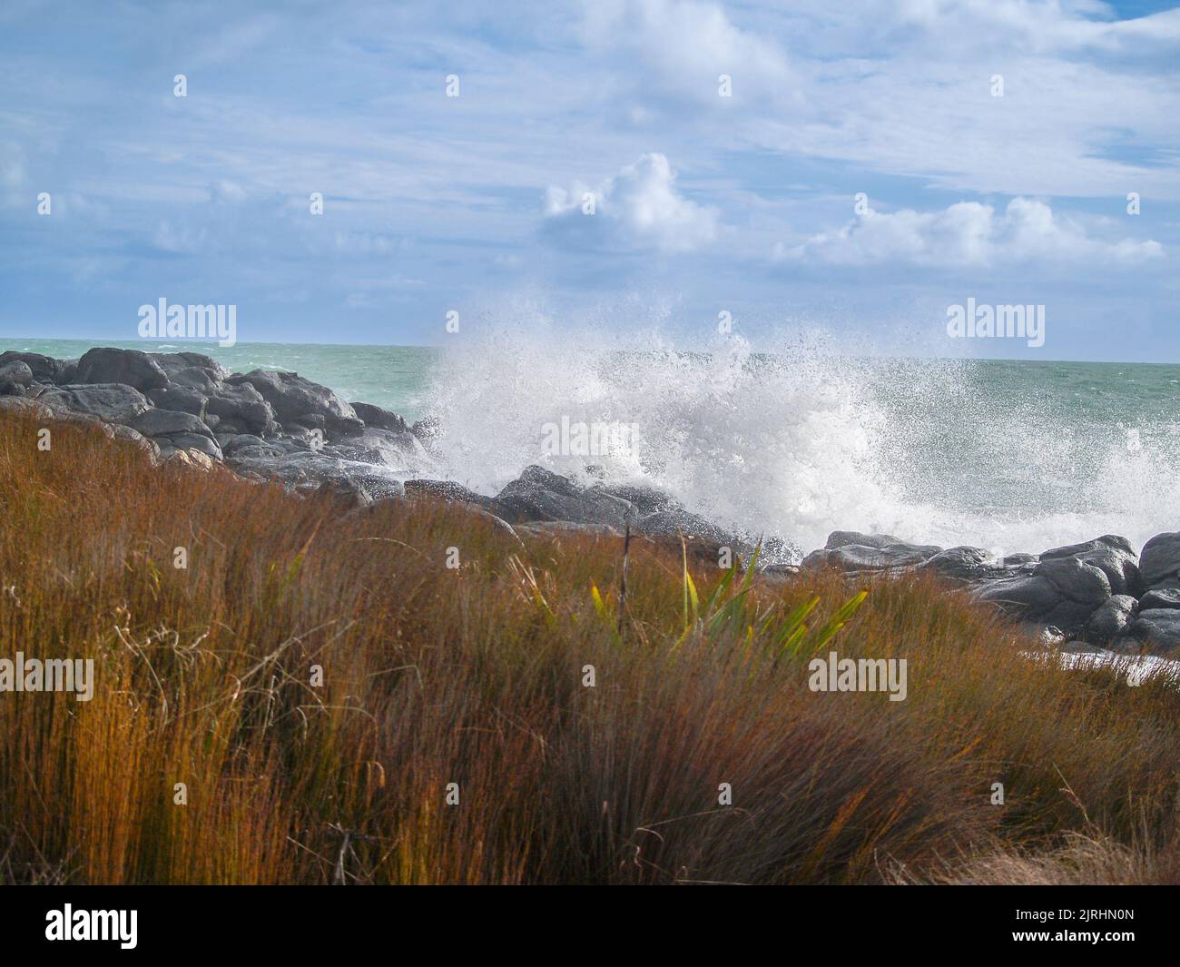 Waves crashing in on rocky foreshore sending sea-spray into air on ...