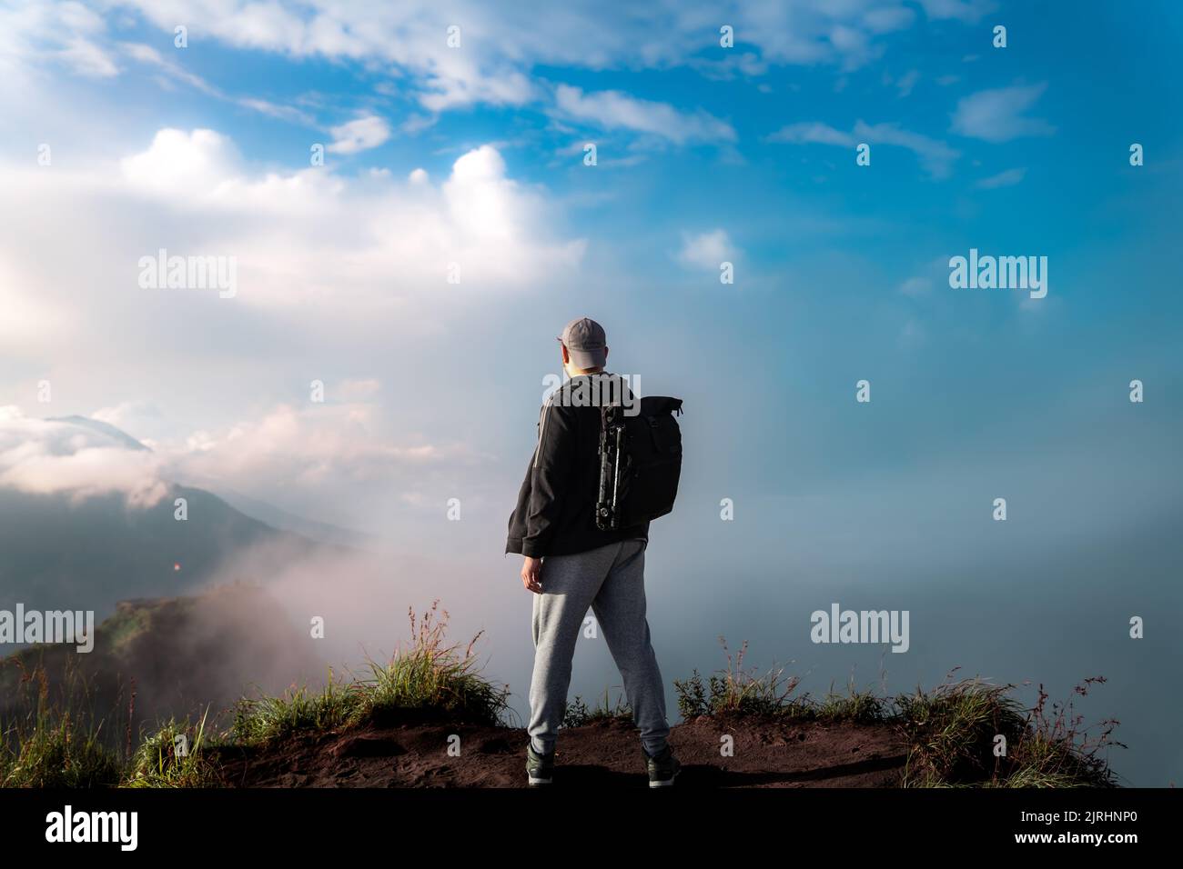A scenic view of a male person standing on top of a volcanic mountain ...