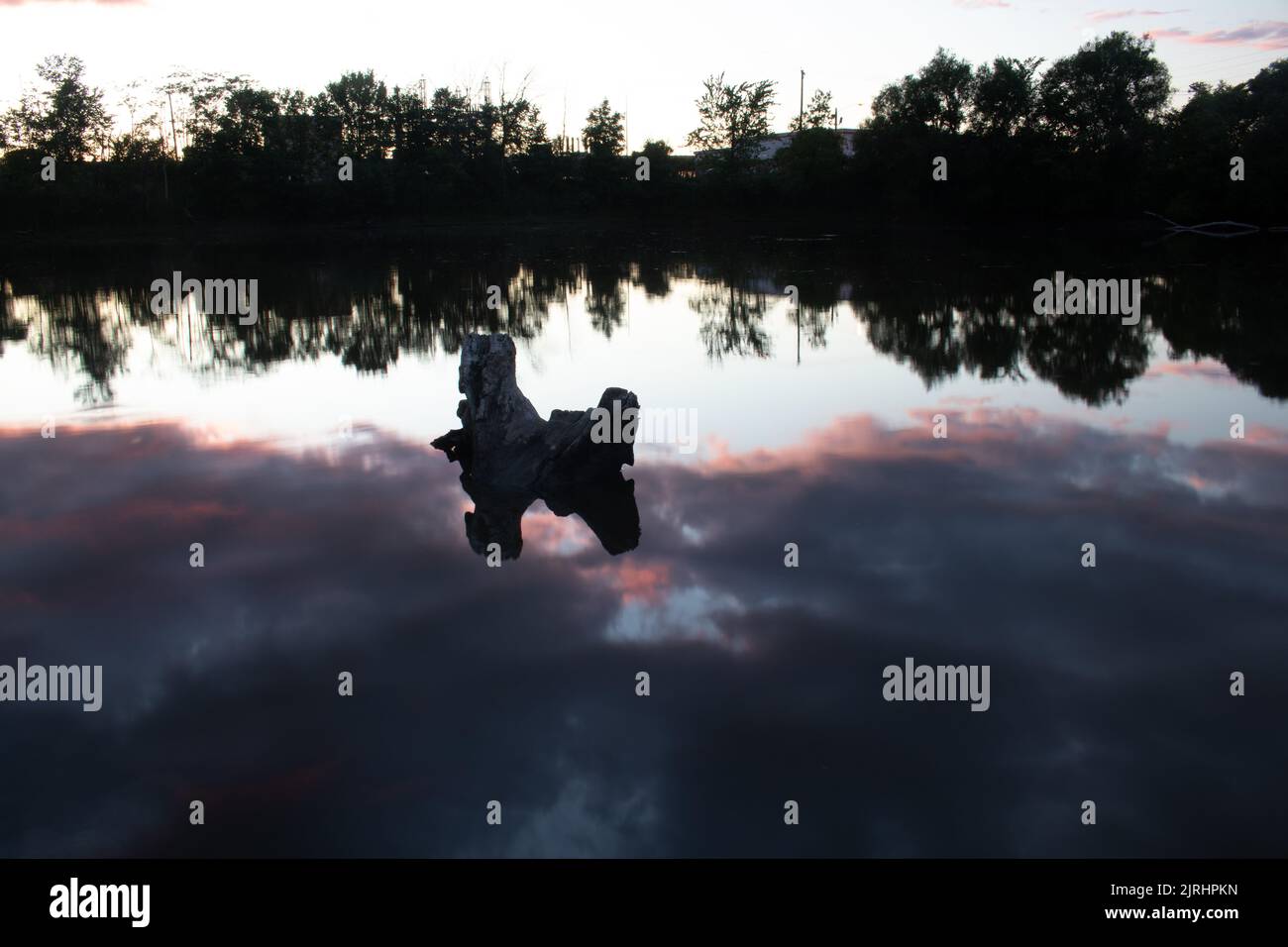 A beautiful landscape of a small calm lake with the cloudy sunset sky ...