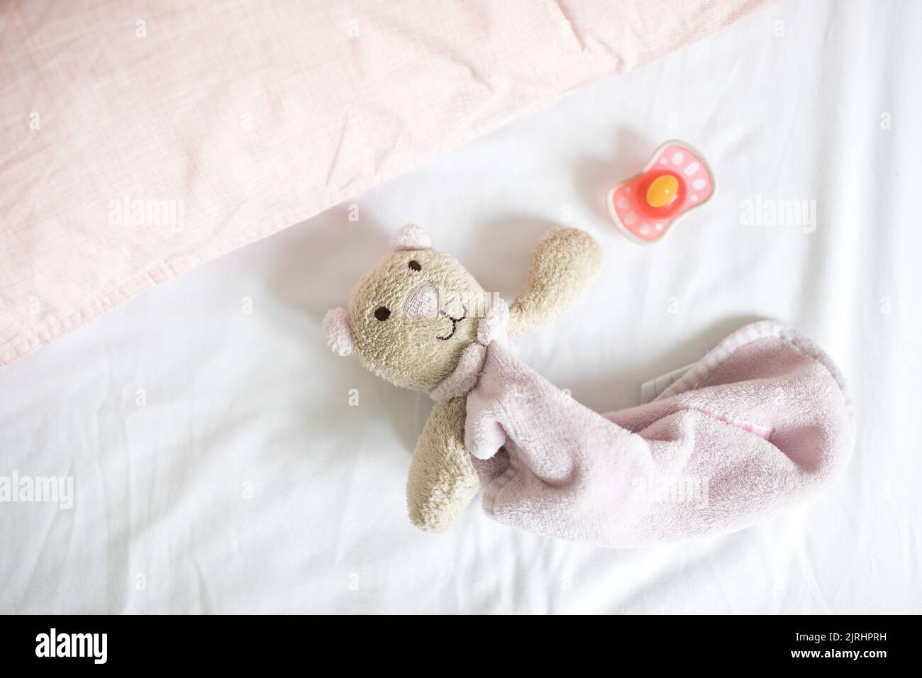 A top view of a small teddy bear and pacifier on bed Stock Photo - Alamy