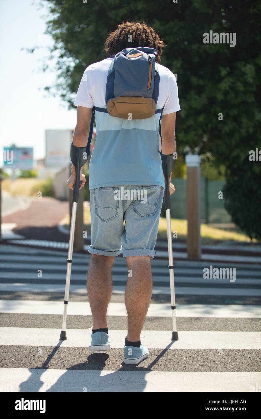 disabled man using crutches to cross the road Stock Photo - Alamy