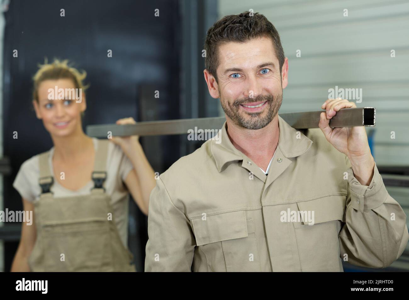 male and female colleagues carrying metal length on their shoulders ...