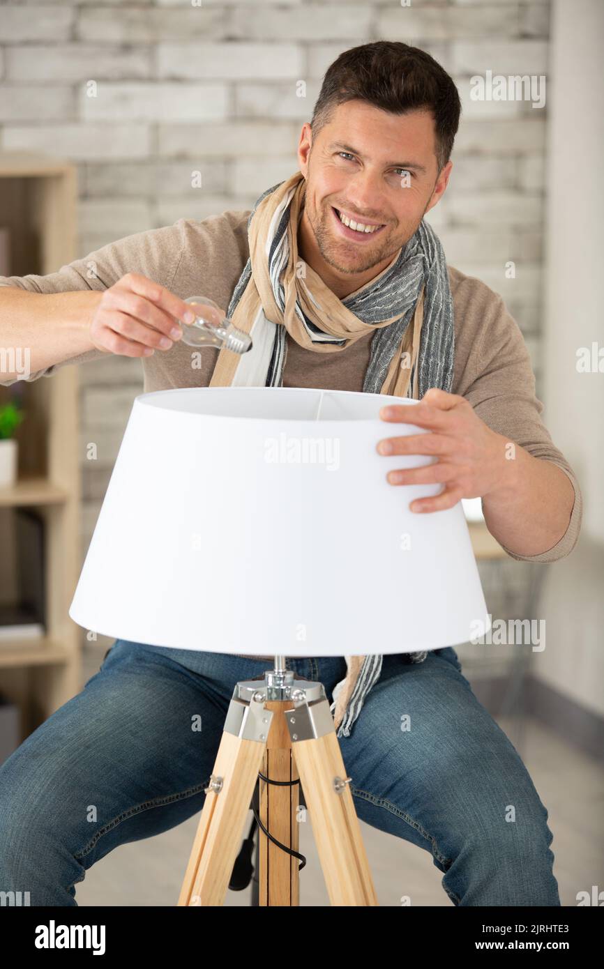 man changing light bulb on floor lamp Stock Photo - Alamy