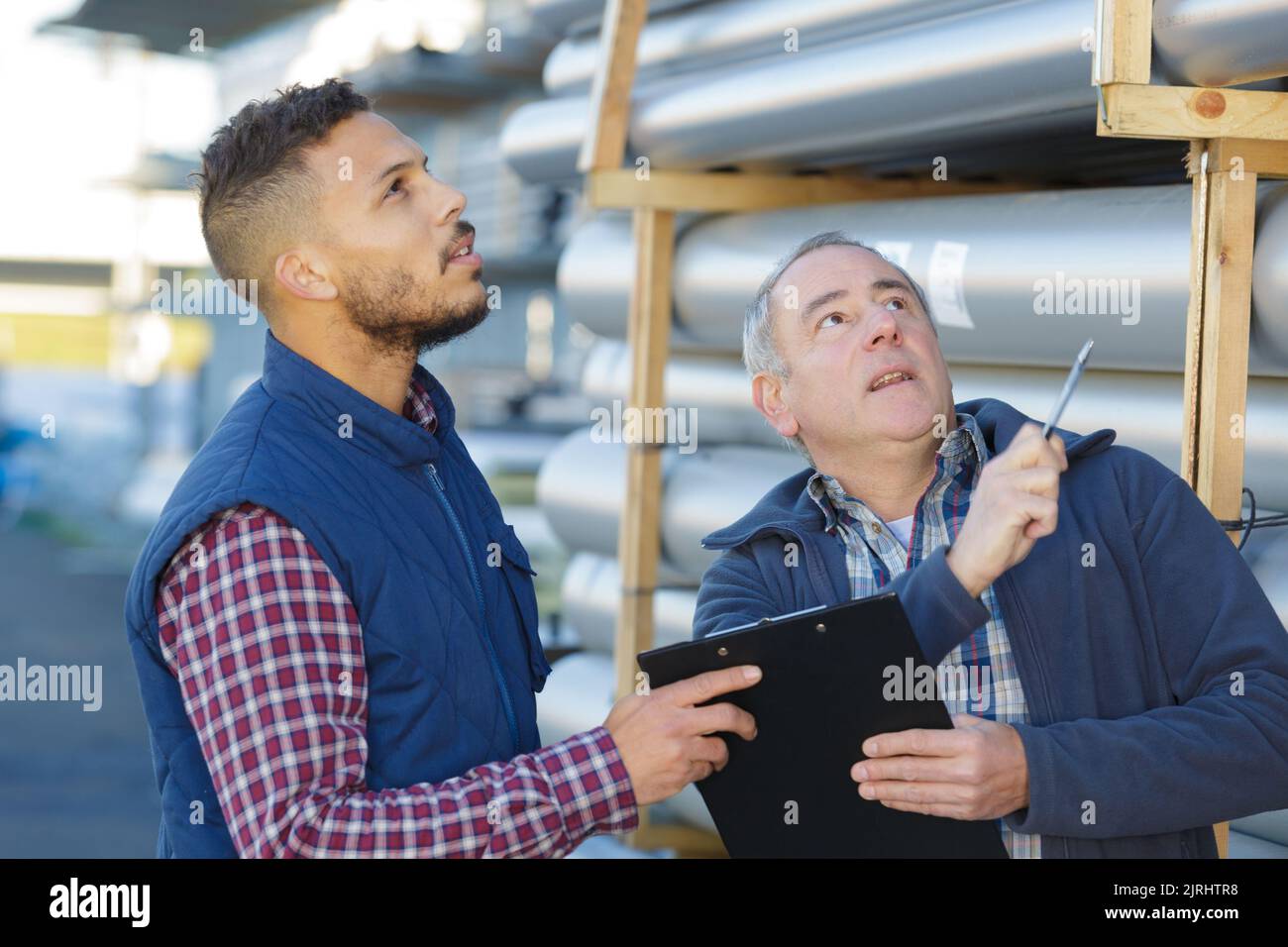 men with clipboard looking up in building materials yard Stock Photo ...
