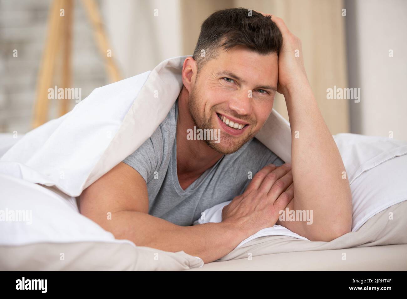 picture showing young man waking up in bed Stock Photo - Alamy