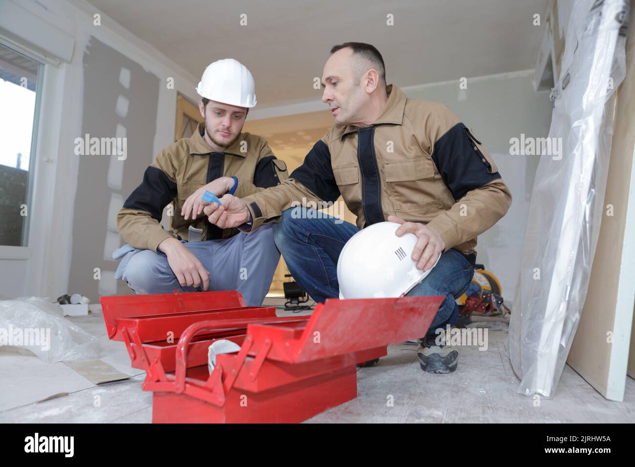 two builders crouched by open toolbox Stock Photo - Alamy