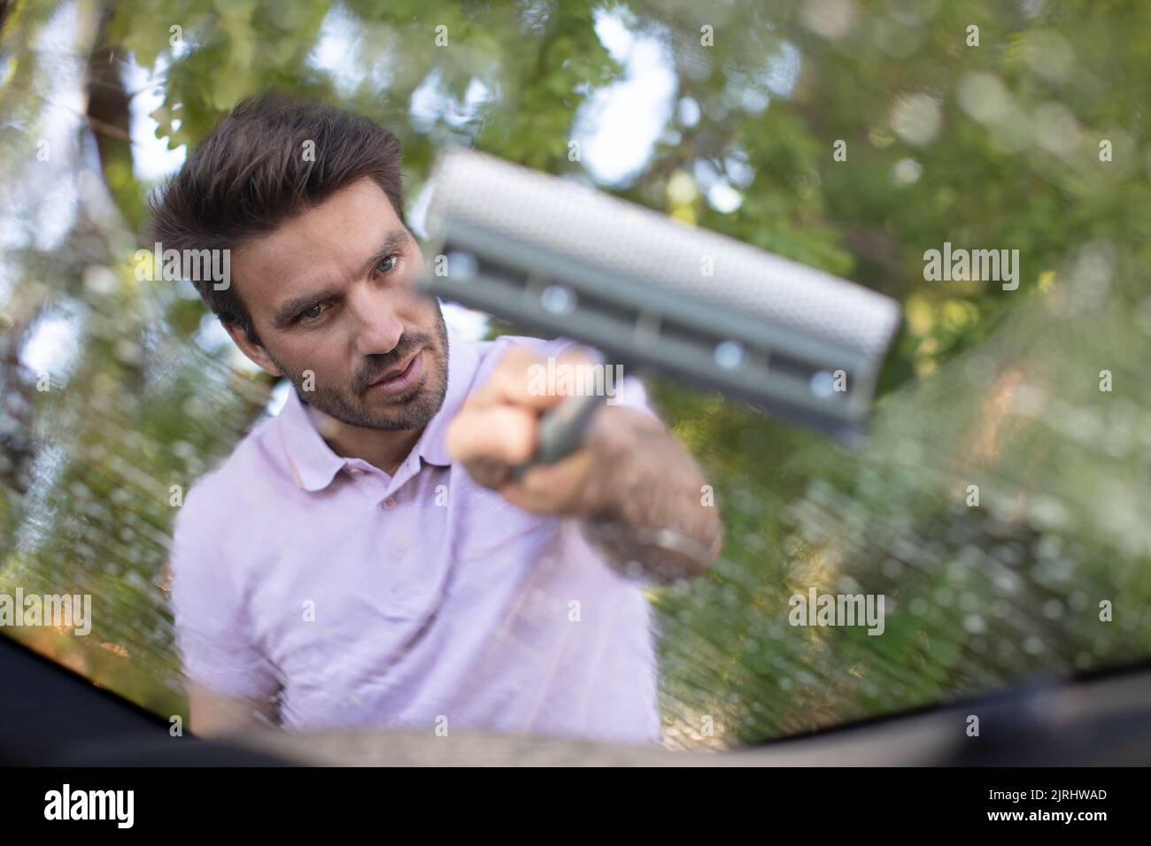 man cleaning a windshield with a squeegee Stock Photo - Alamy