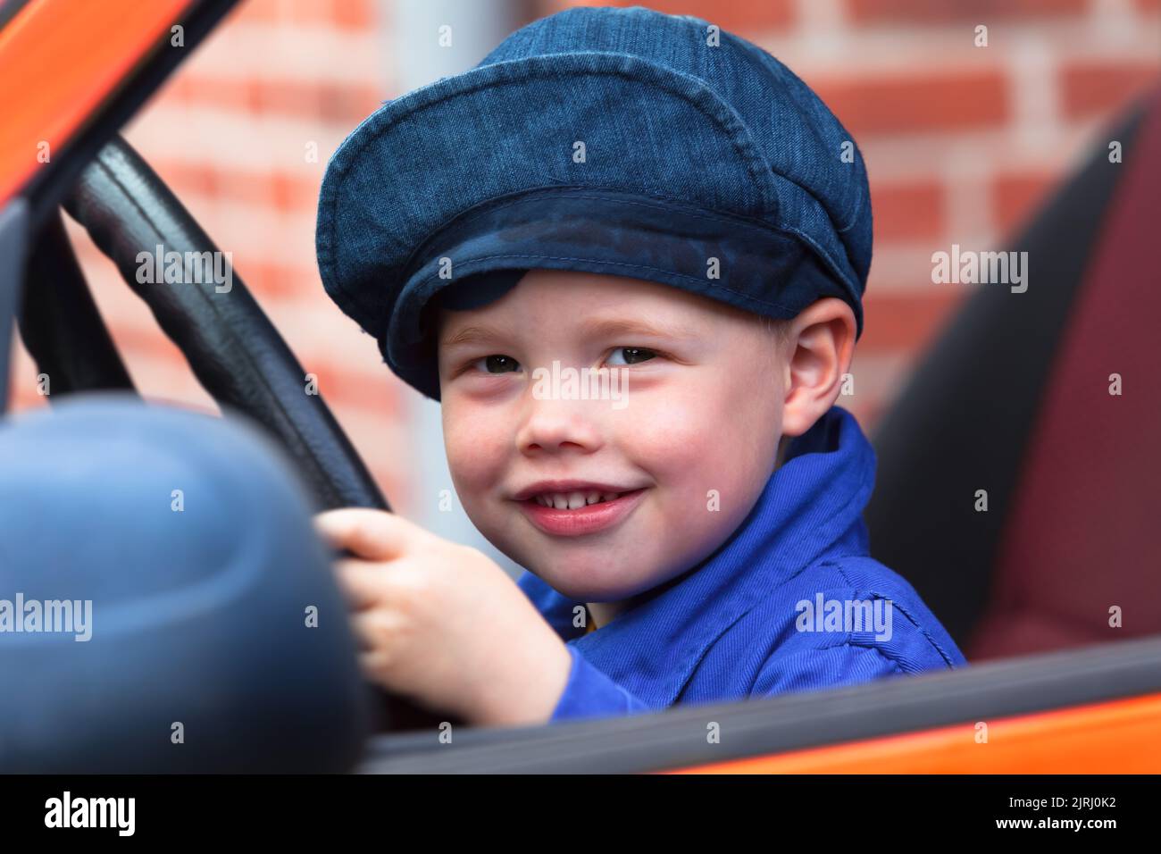 Cute little rascal child sitting in dads car on steering wheel and ...