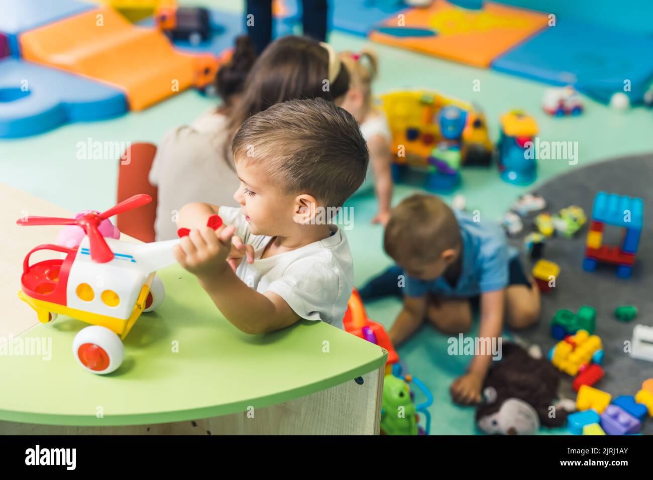Nursery school. Toddlers on the floor playing with different plastic ...