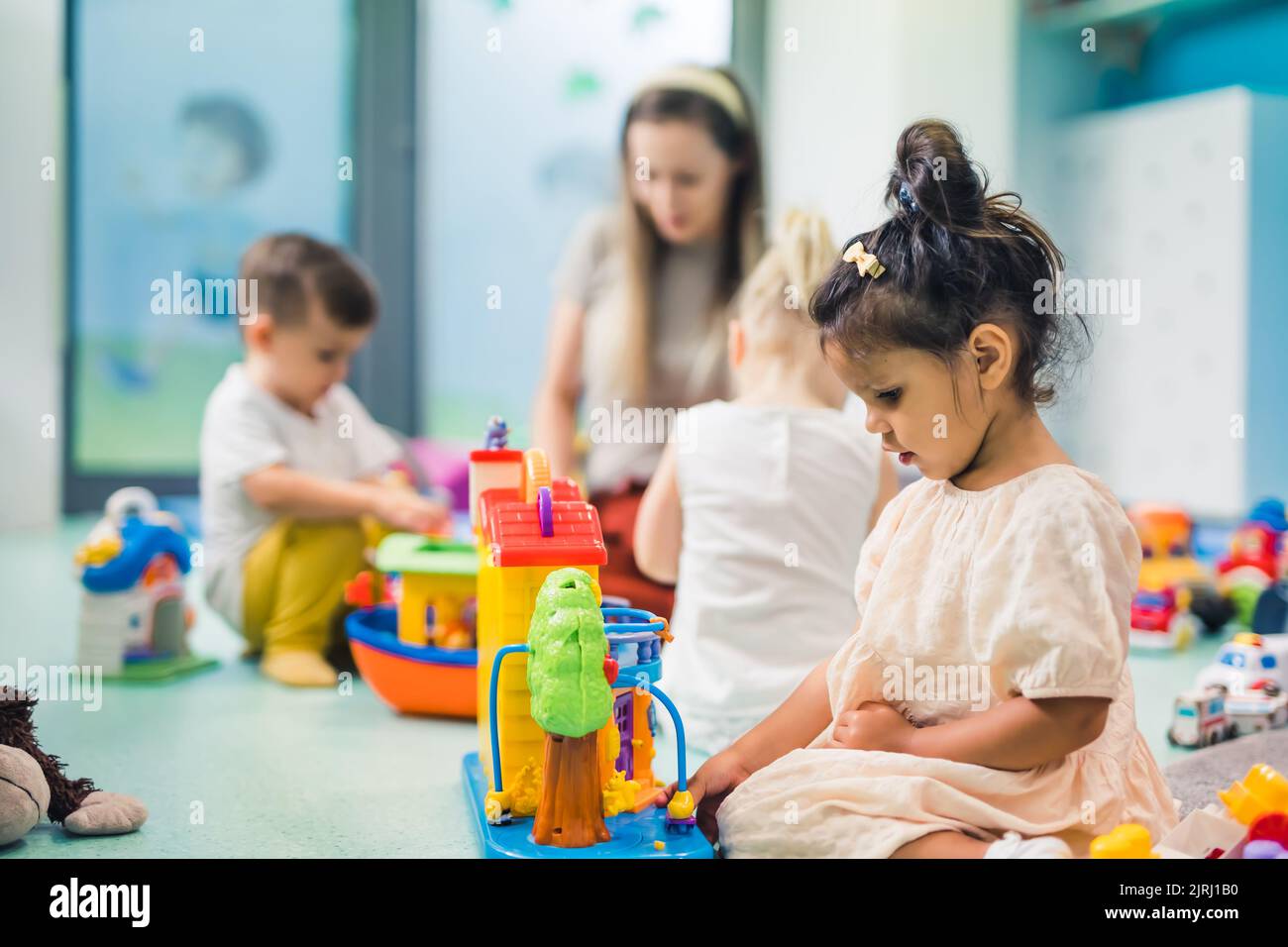 Learning through play at the nursery school. Little girl, other ...