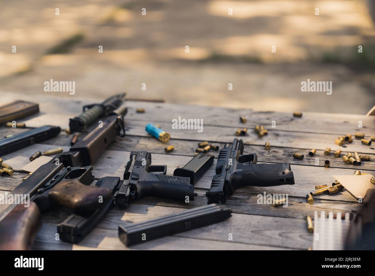 Rifle and guns stored on wooden table with bullets ammunition clips and shells. Military ...