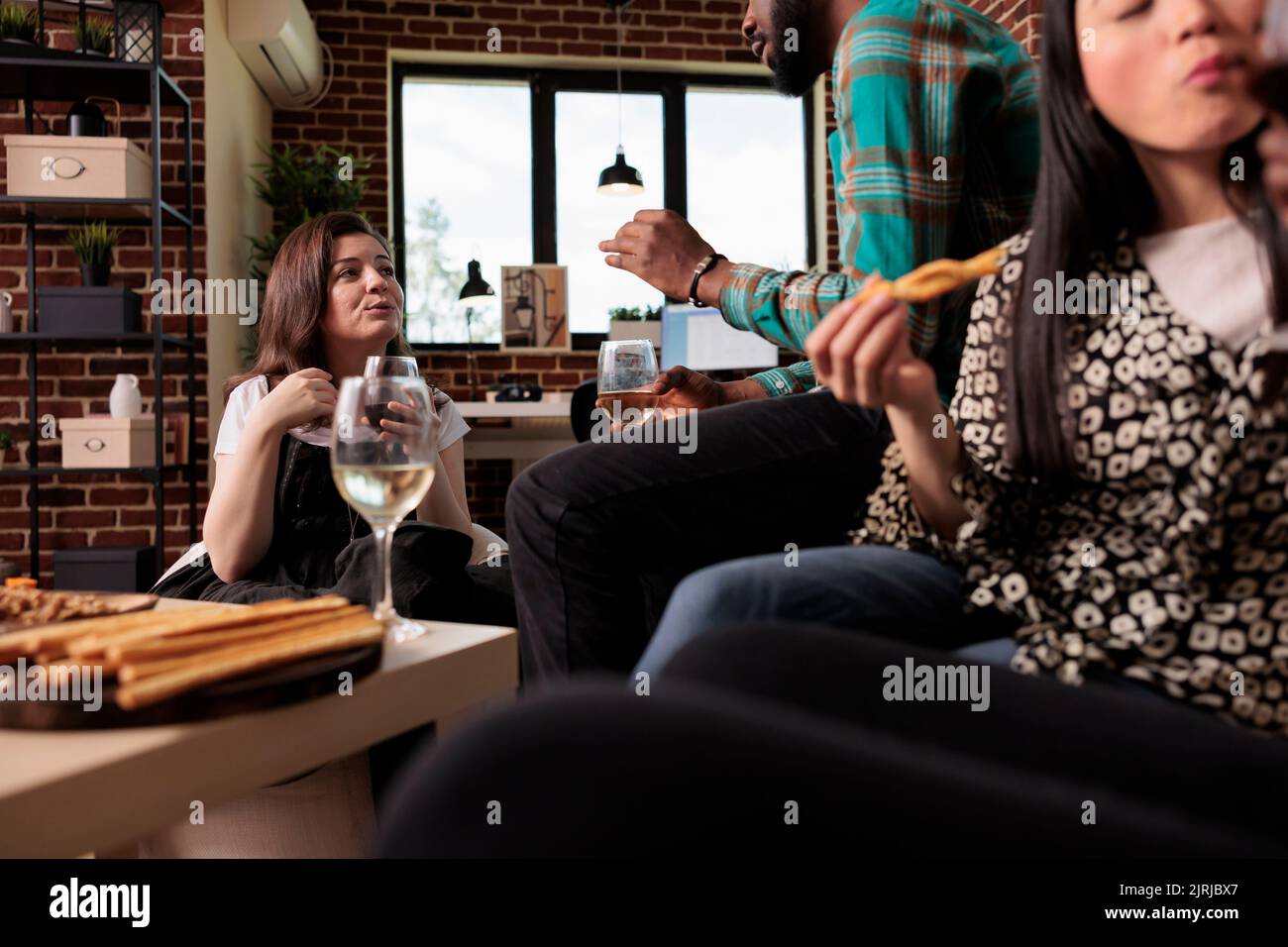 Multiethnic group of close friends sitting in living room while having ...