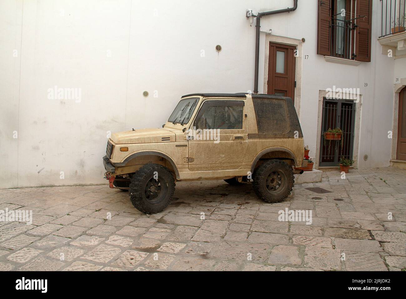 A muddy off-road vehicle parked on a city street in Italy Stock Photo ...