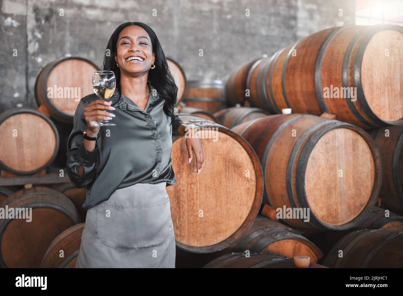 Portrait, woman and winemaker with a glass with wood barrels of white ...