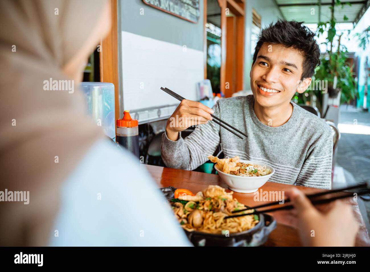 close up of male customer holding chopsticks enjoying chicken noodles ...