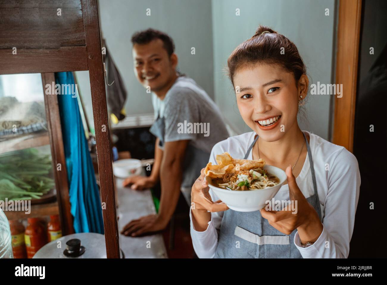 female waitress smiling while bringing a bowl of chicken noodles Stock ...
