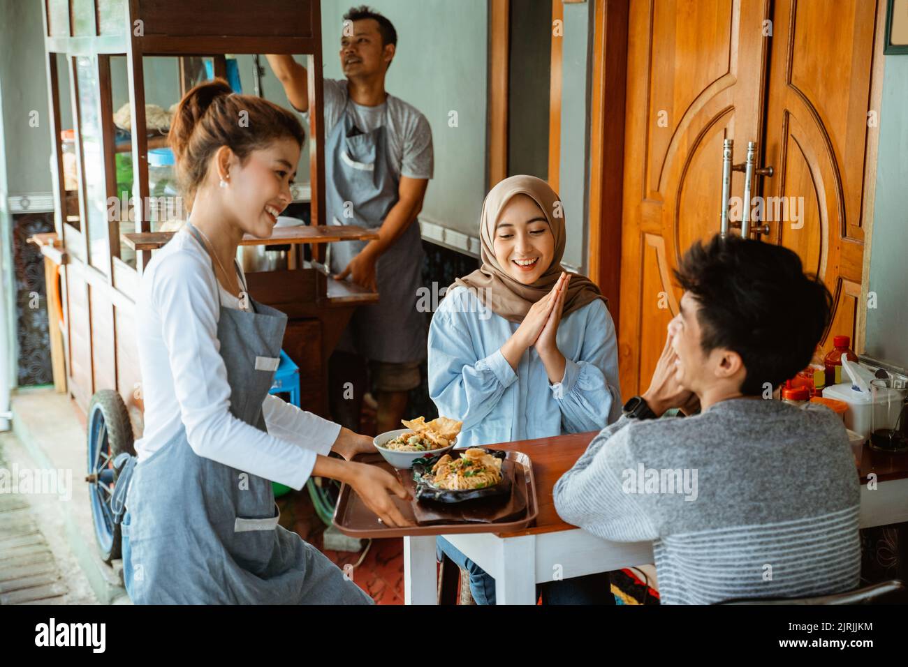 female waitress serving chicken noodles and fried noodles to customers ...