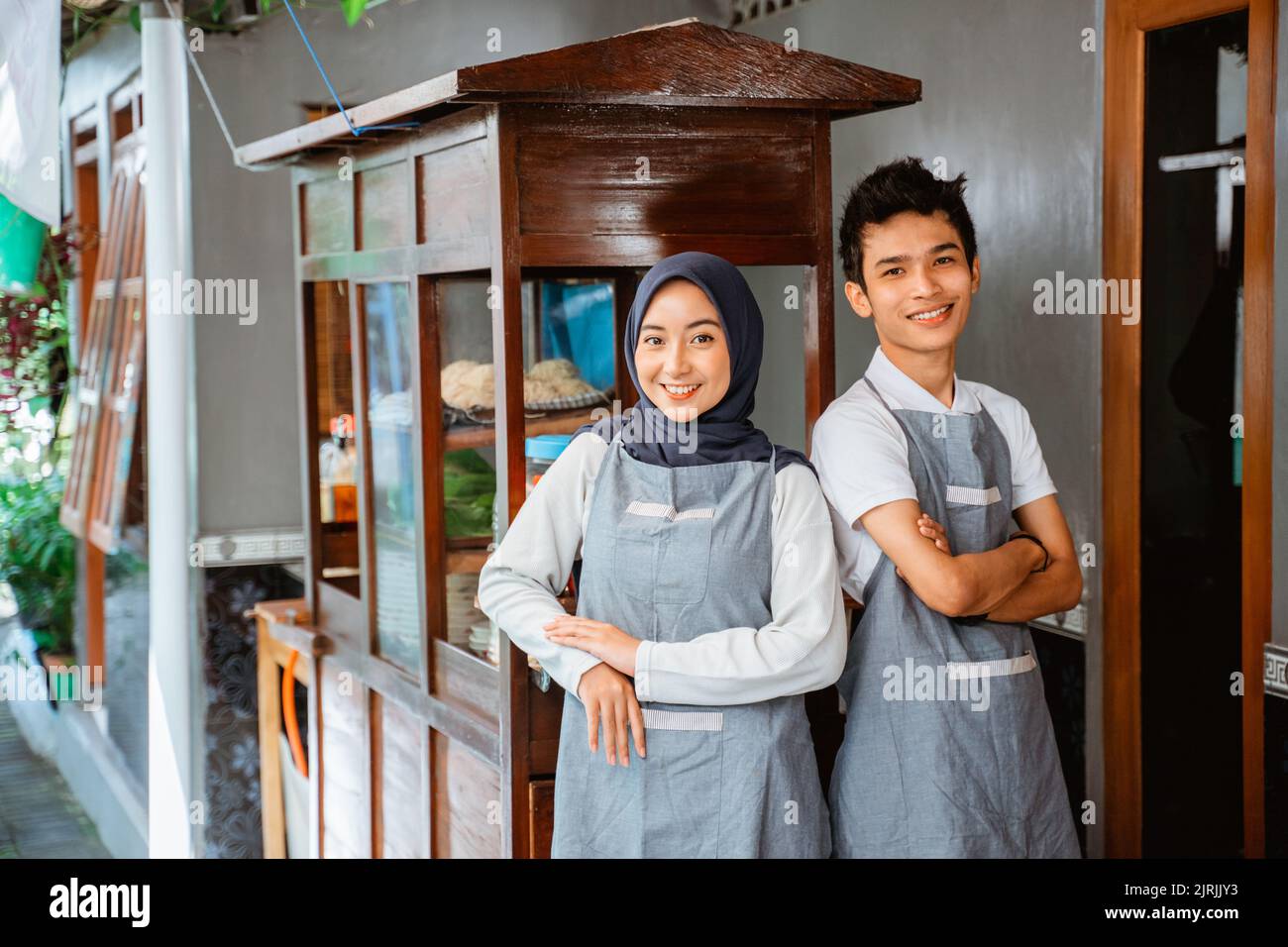 a couple of sellers with their hands crossed smiling Stock Photo - Alamy