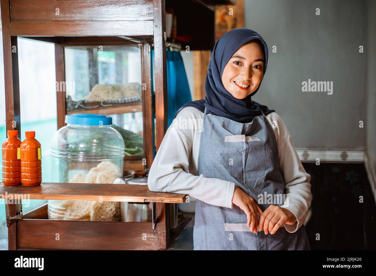 Asian hijab woman wearing apron smiling while standing beside cart ...